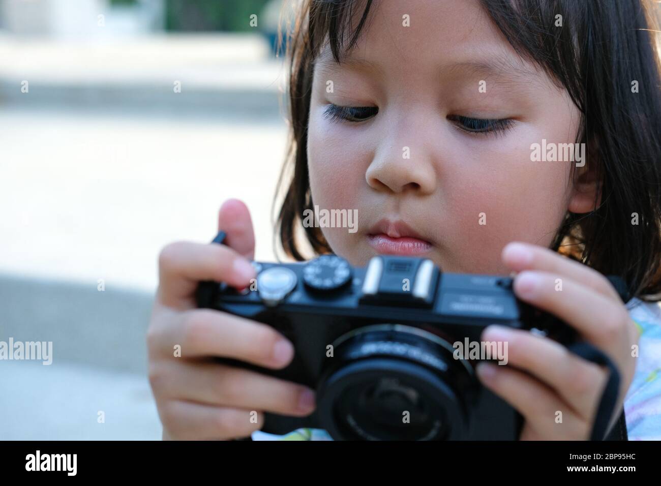 Kid, Child, Asian little girl holding and looking at the digital camera ...