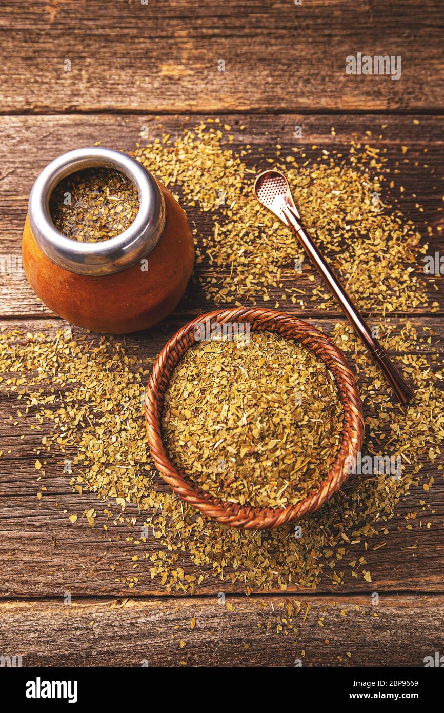 Yerba mate in calabash and dry herb in wooden bowl on wooden background ...