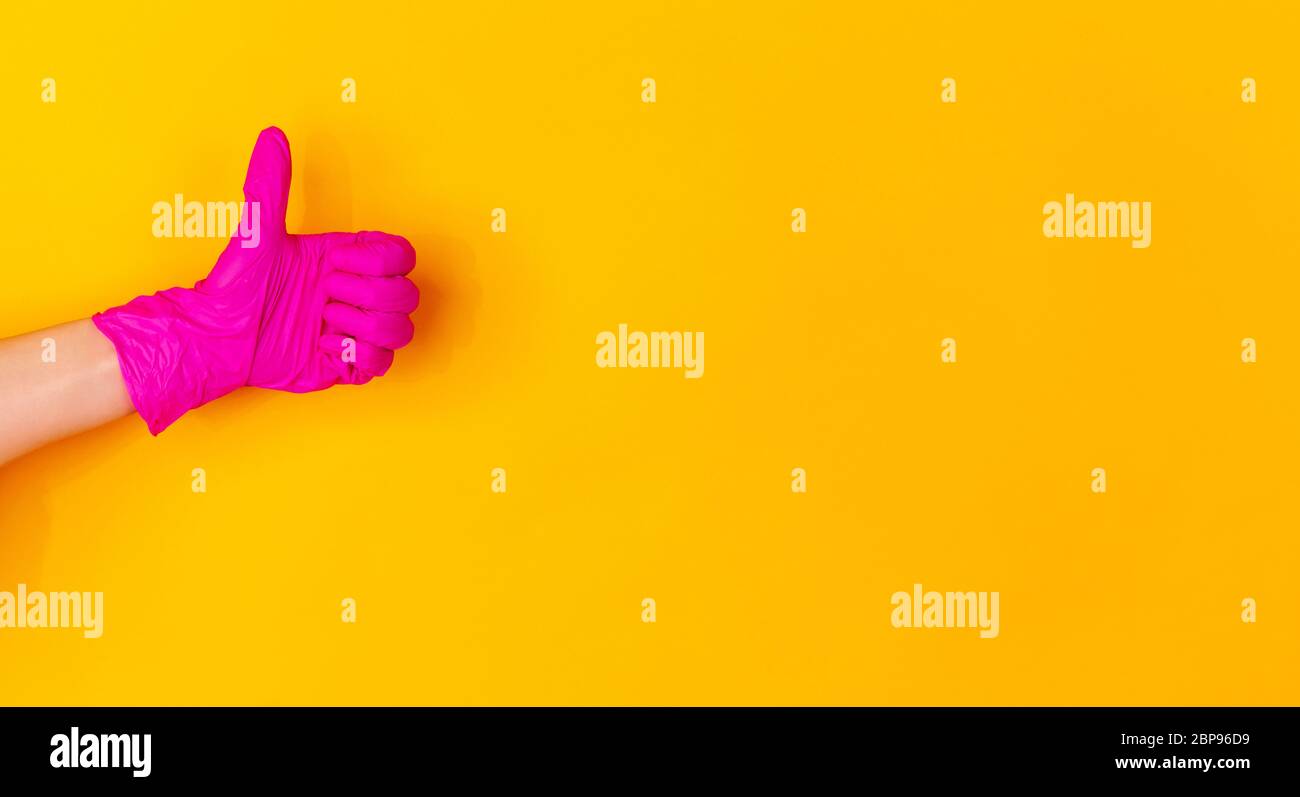 Hand in pink protective rubber glove showing thumb up isolated on ...