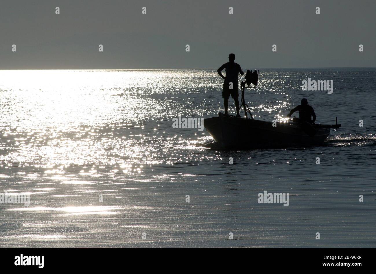 Boat sailing away at sundown Stock Photo - Alamy