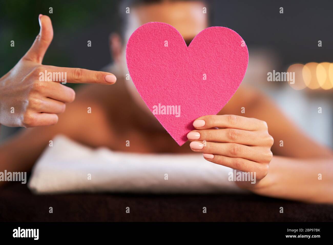 Relaxed woman waiting for a back massage and holding heart Stock Photo ...