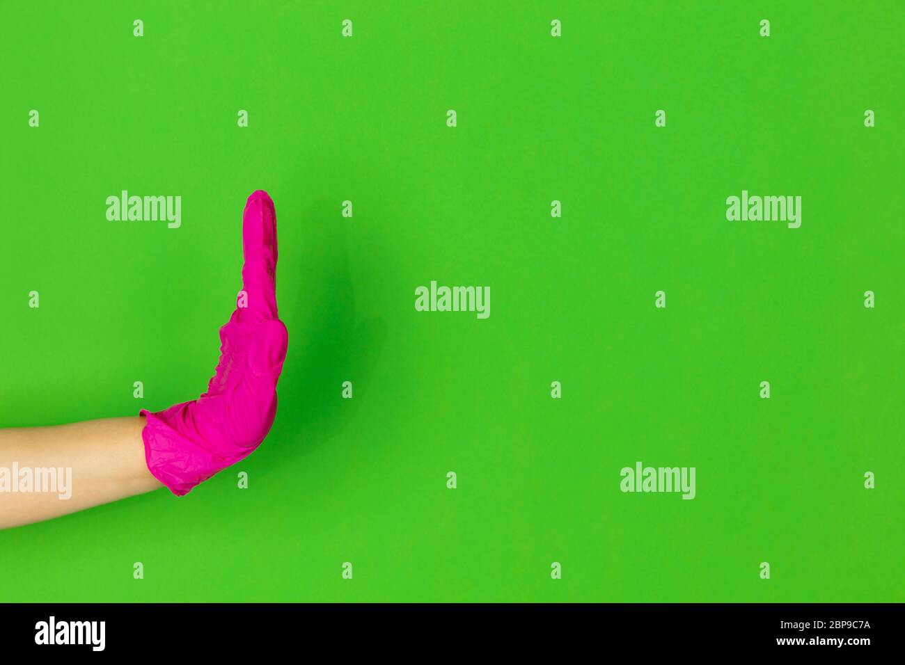 Hand in pink protective rubber glove clapping isolated on green studio ...