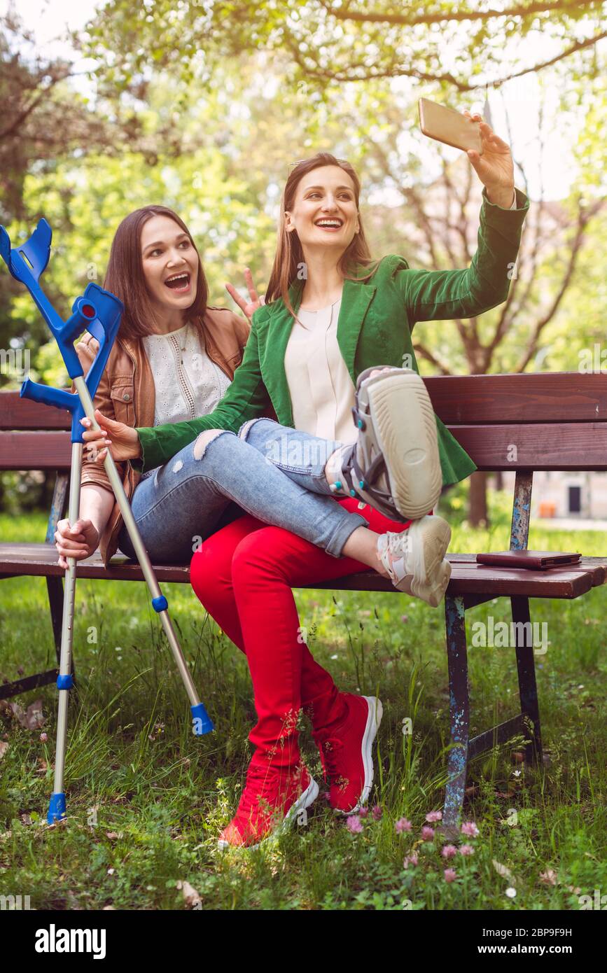 Best friends with one having a broken leg taking a selfie on the phone ...