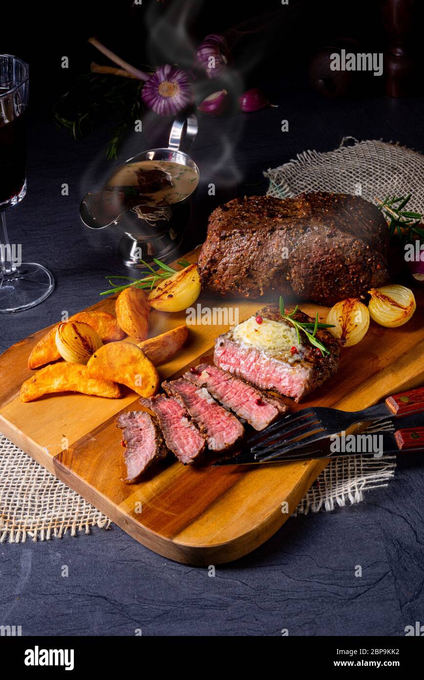 rustic medium butter beef steak with herbs and potato wedges Stock ...