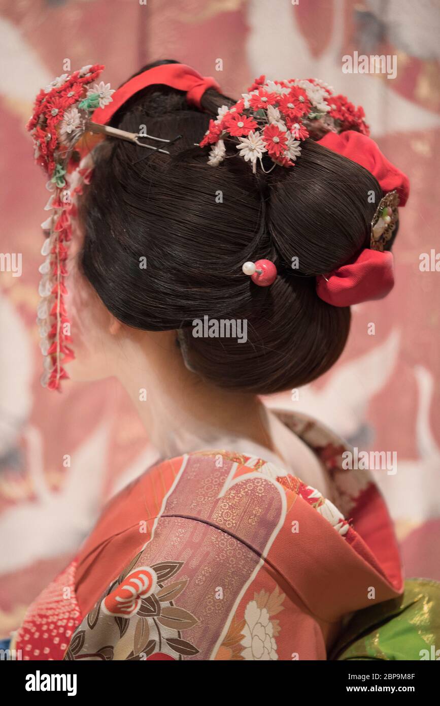 Maiko or geisha in red kimono back coifed hair brooch with patterns of ...