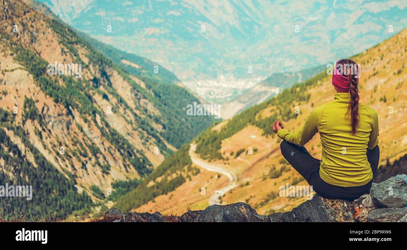Female Sitting On Top Of High Hill In Meditating Pose Looking At Scenic ...