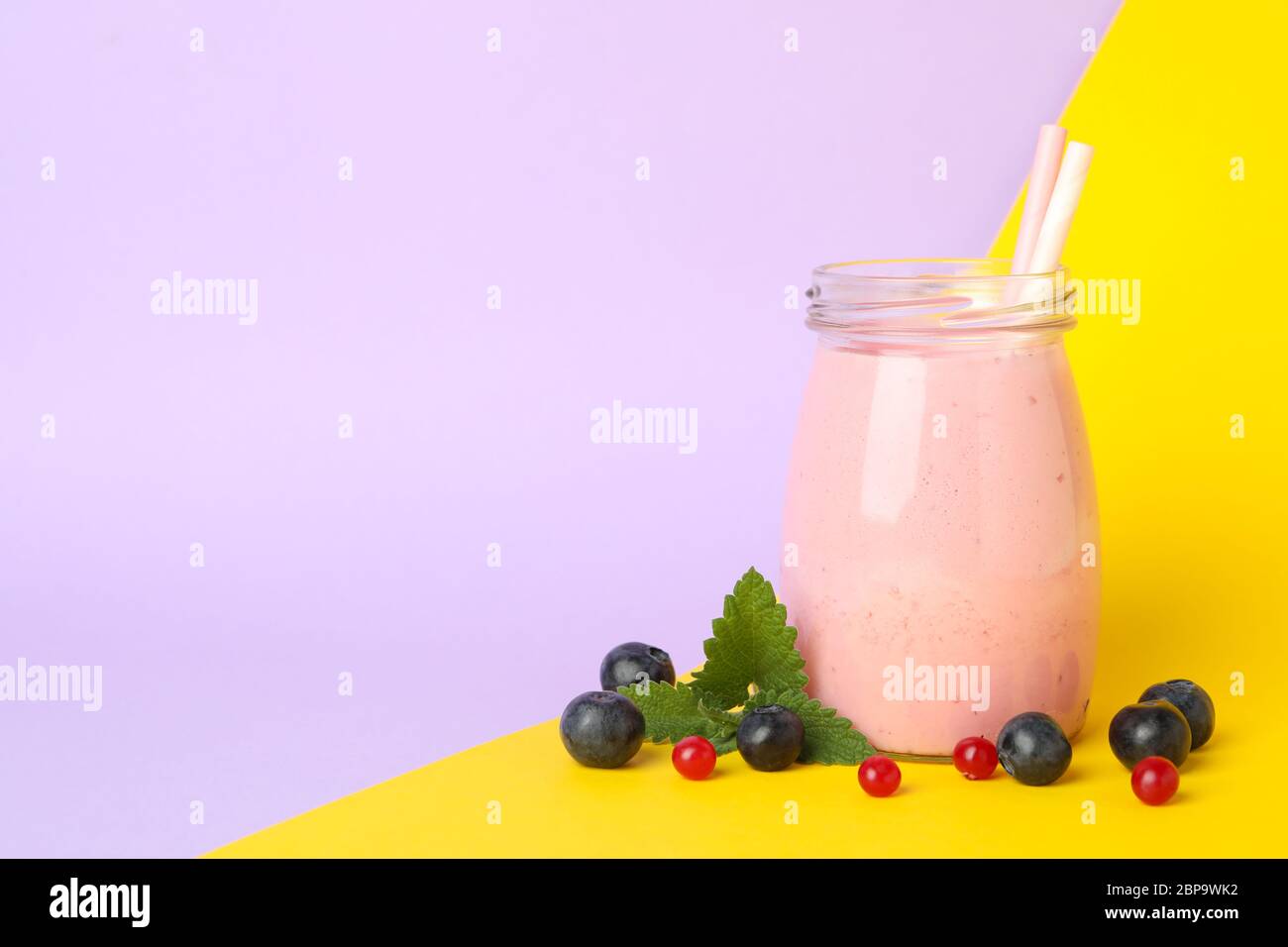 Glass of berry milkshake on two tone background. Summer drink Stock ...