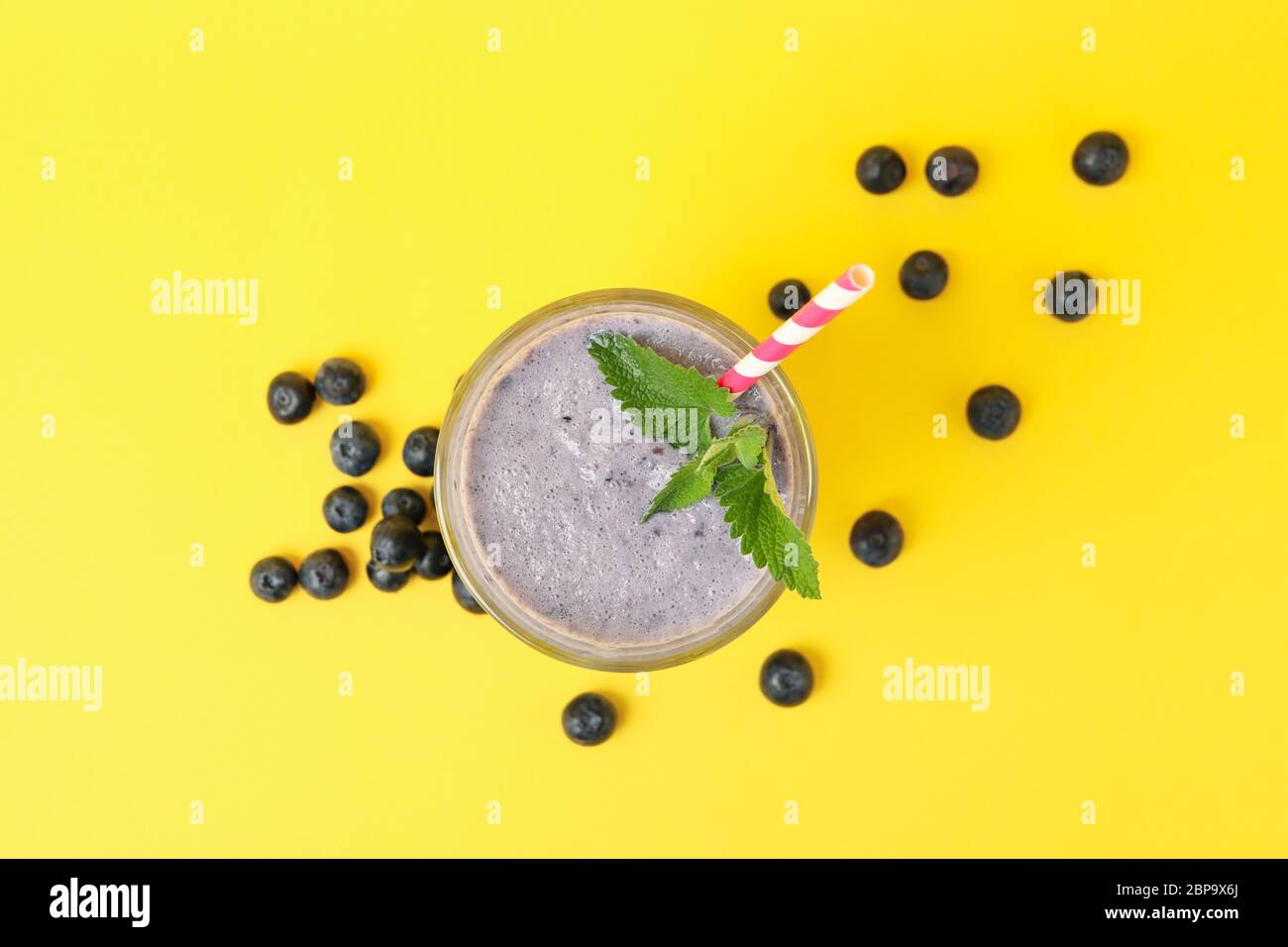 Glass of delicious berry milkshake on yellow background. Summer drink ...
