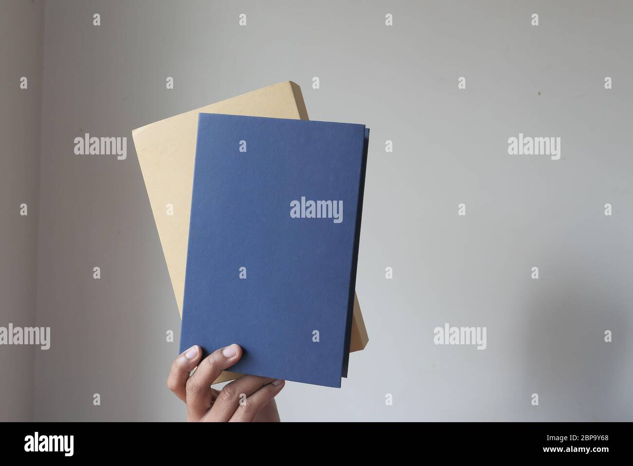 hand holding books against a wall Stock Photo - Alamy