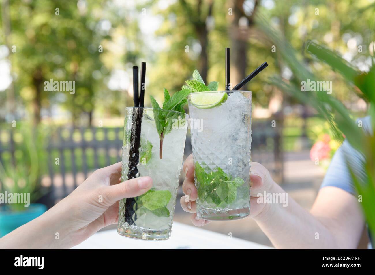 Two women drinking mojito cocktail at outdoor bar restaurant. Summer ...