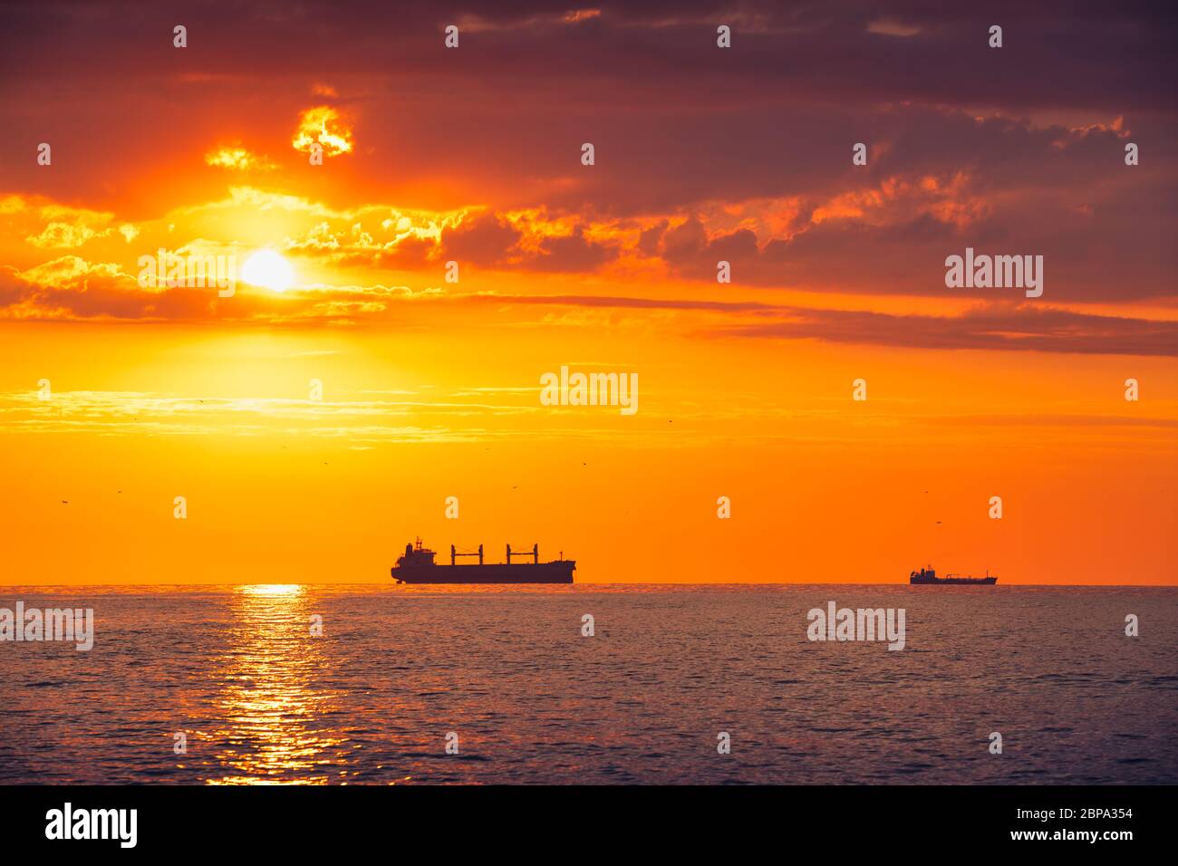 Sun setting at the sea with sailing cargo ship, scenic view Stock Photo ...