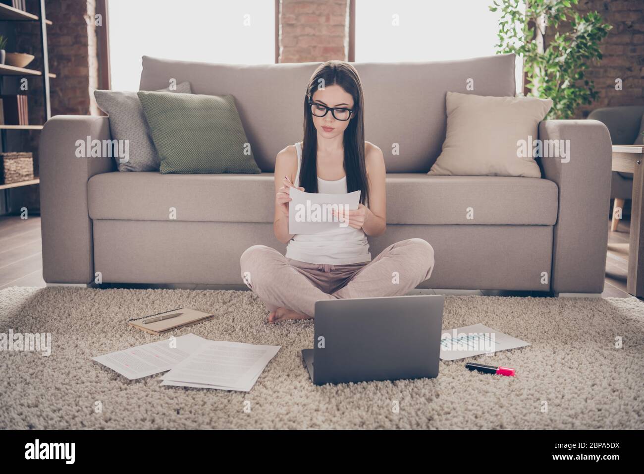 Full length photo of focused smart girl sit carpet legs crossed hold ...