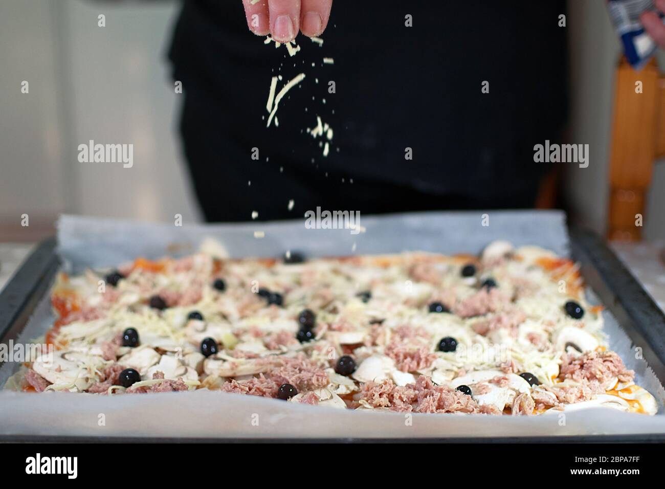 Traditional pizza cooking by italian chef at home. Adding some cheese ...