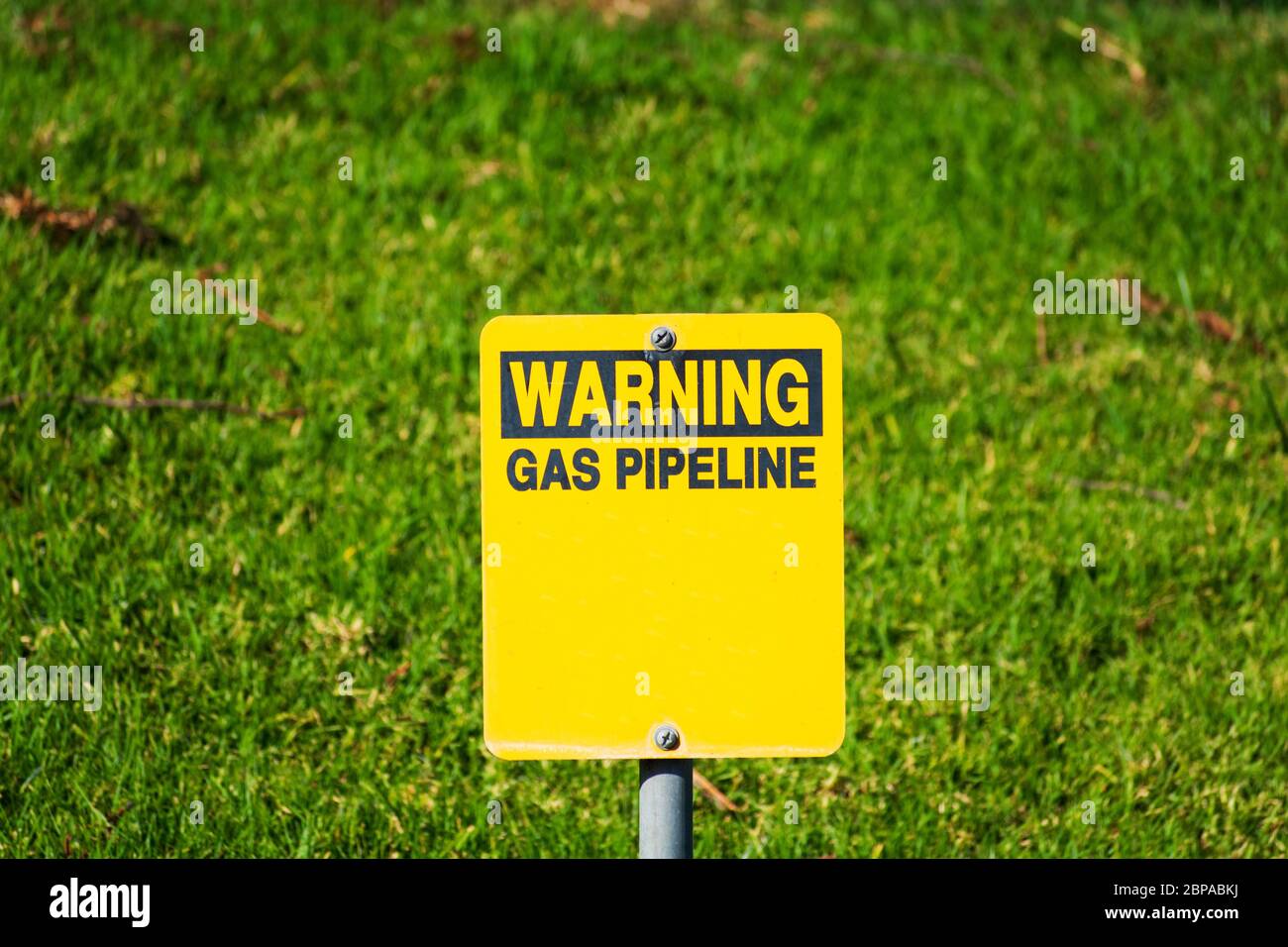 Warning gas pipeline sign with blurred background of green landscape ...