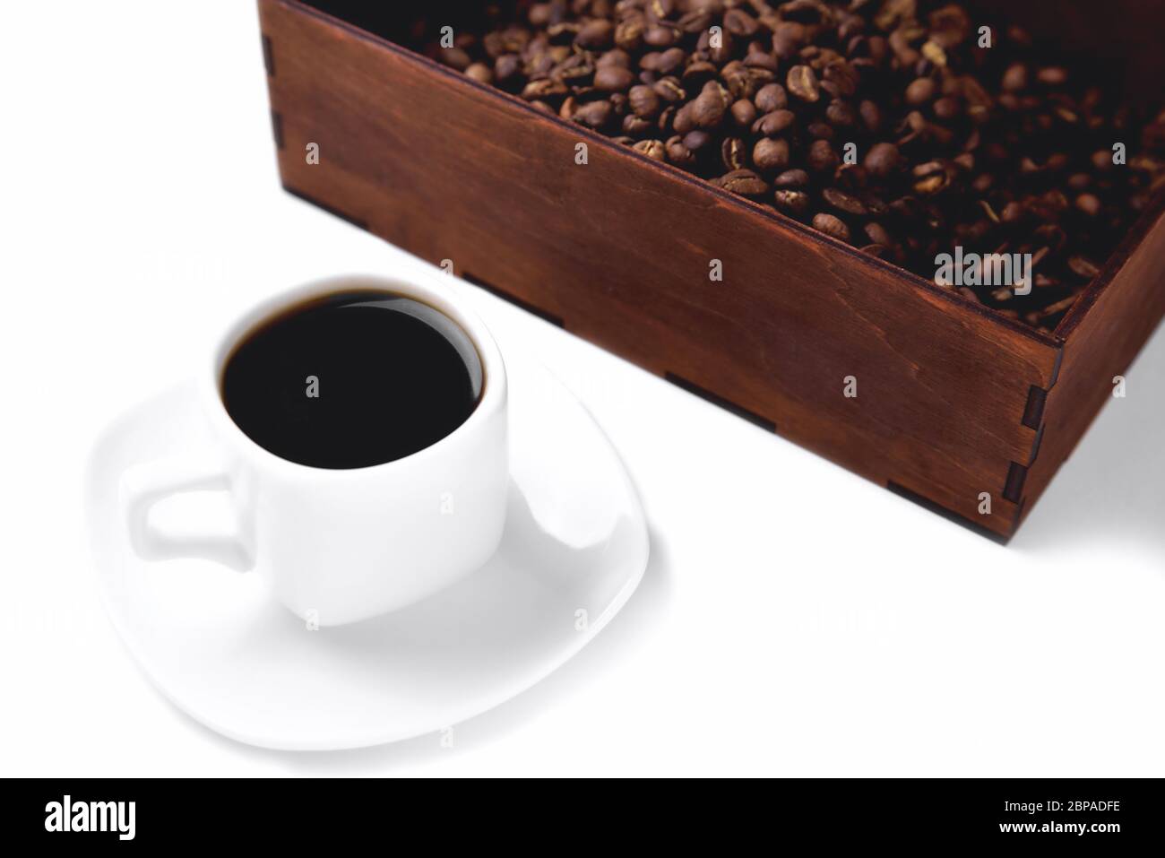 white cup of coffee on a white saucer, natural wooden box with coffee ...