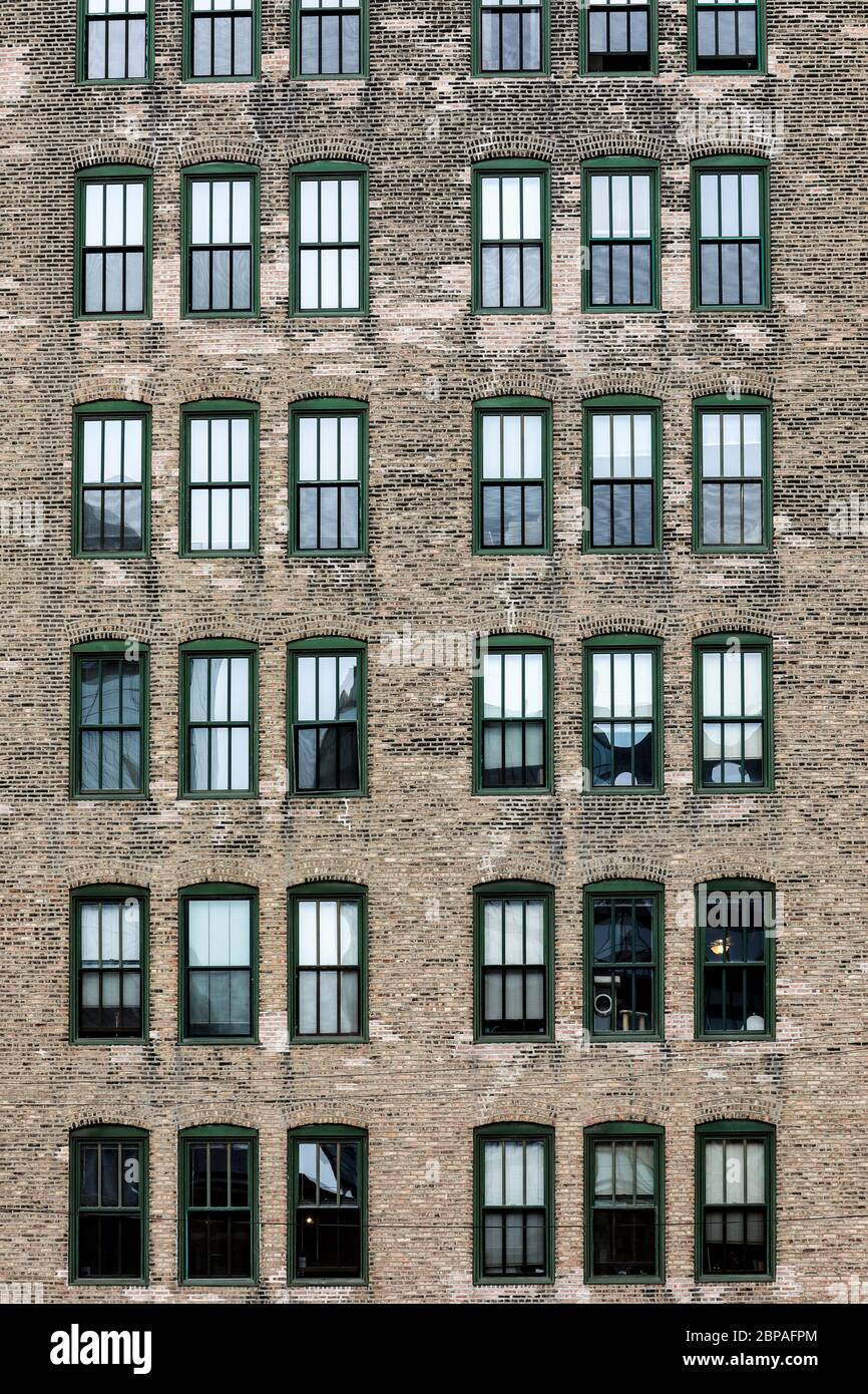 Wall of tightly spaced outside windows with green frames on a six story ...