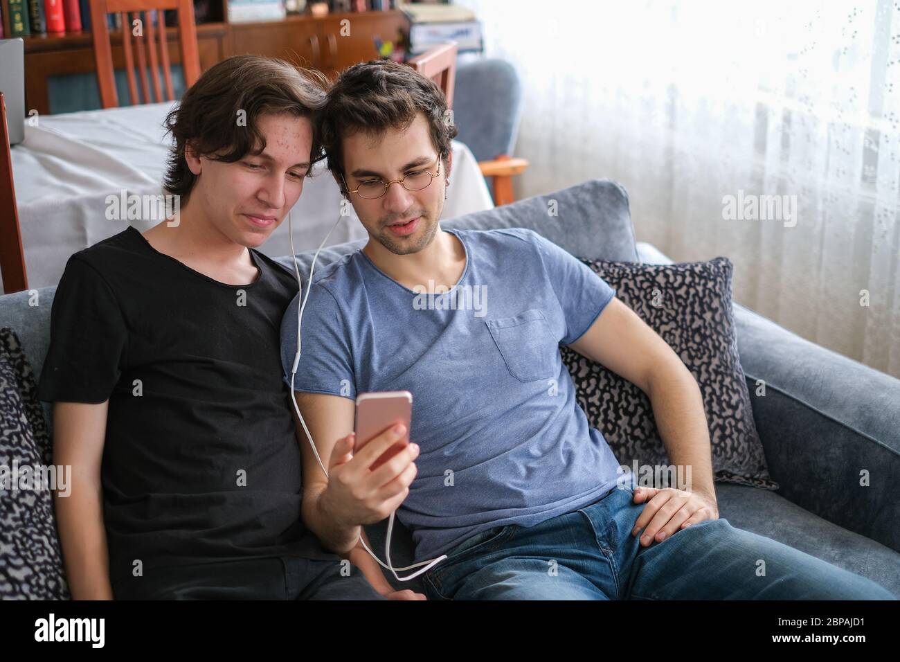 Two brothers are video chatting on smart phone with their father in ...