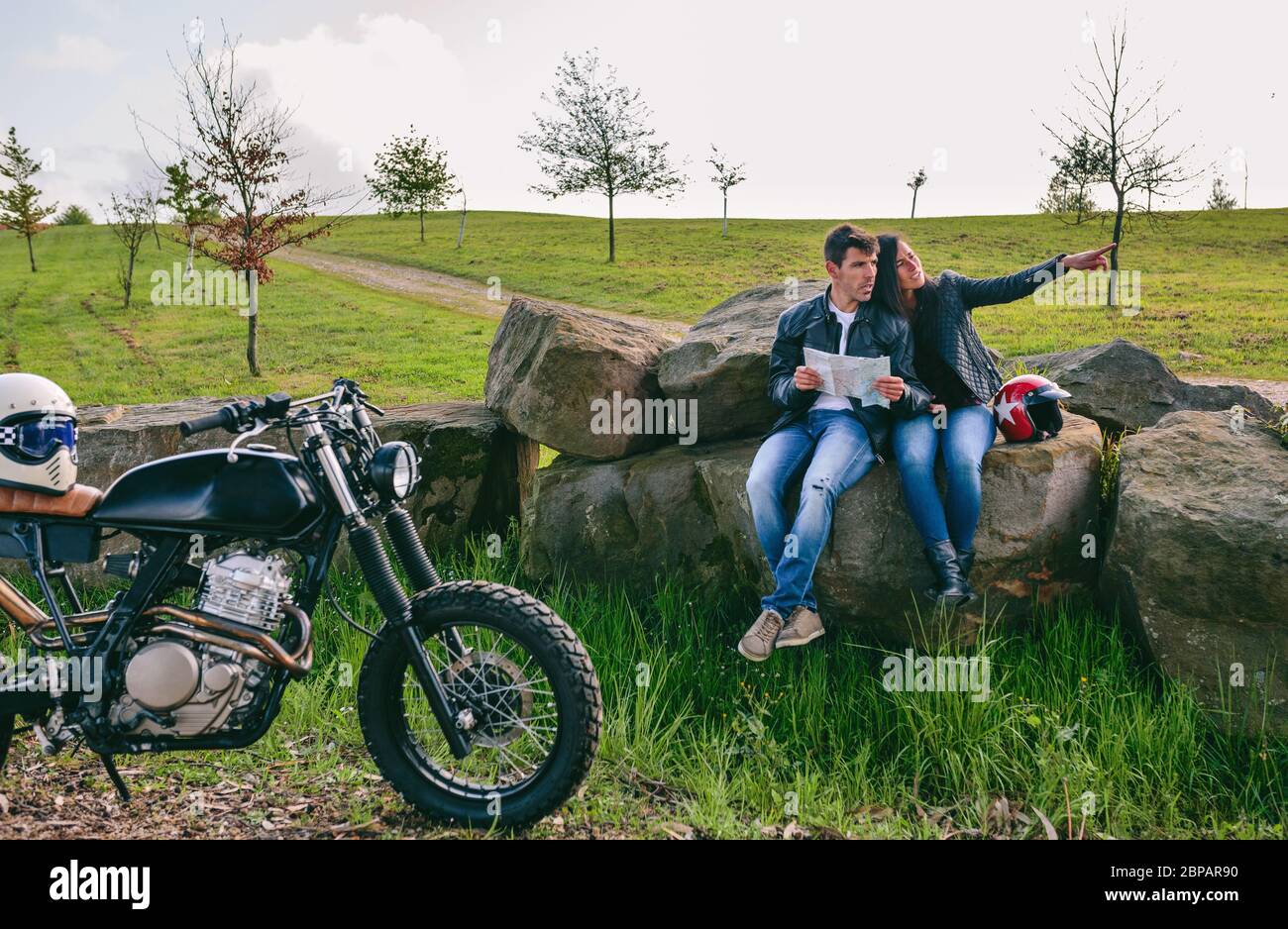 Couple sitting looking at a map with motorcycle Stock Photo - Alamy