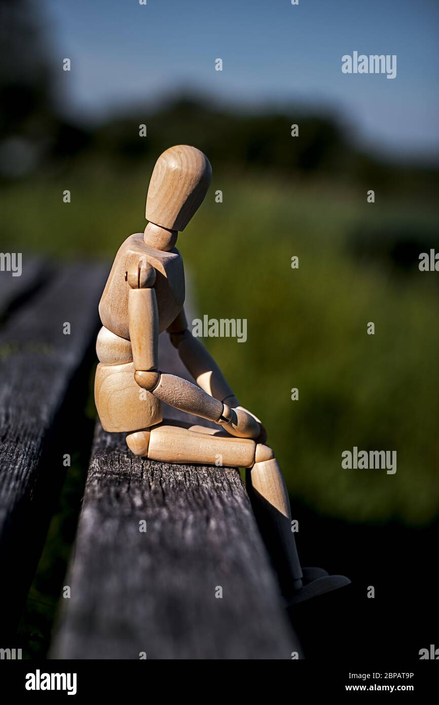 wooden puppet sitting alone on a bench Stock Photo - Alamy