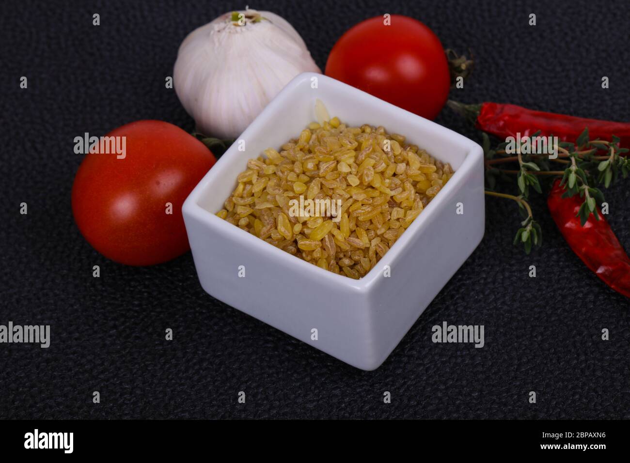 Raw golden bulgur in the bowl with tomatoes and garlic Stock Photo - Alamy