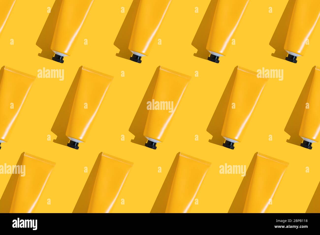 Pattern of yellow tubes of sunscreen on bright yellow background with ...
