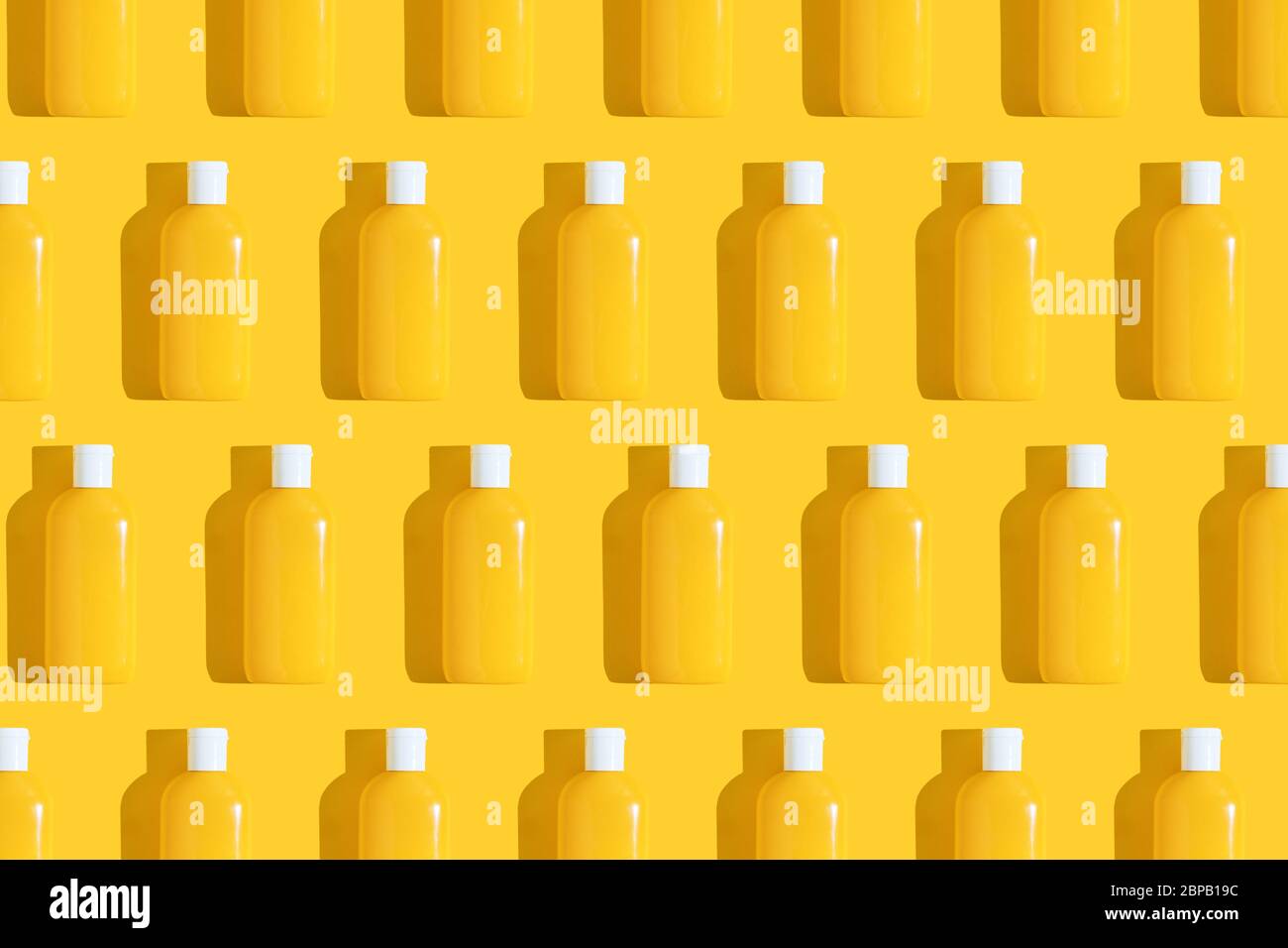 Pattern of yellow tubes of sunscreen on bright yellow background with ...