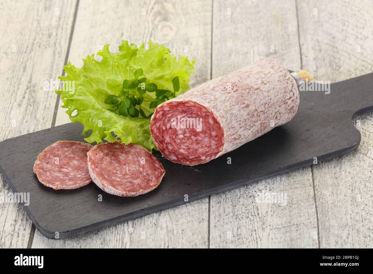 Italian dry Saliami pork sausage served salad leaves Stock Photo - Alamy
