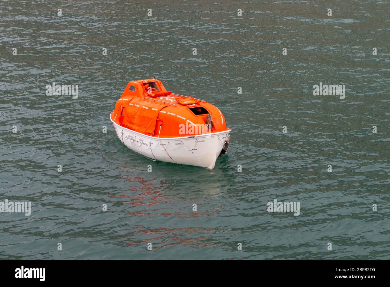 Maneuvering orange lifeboat in water in Arctic waters, Svalbard ...