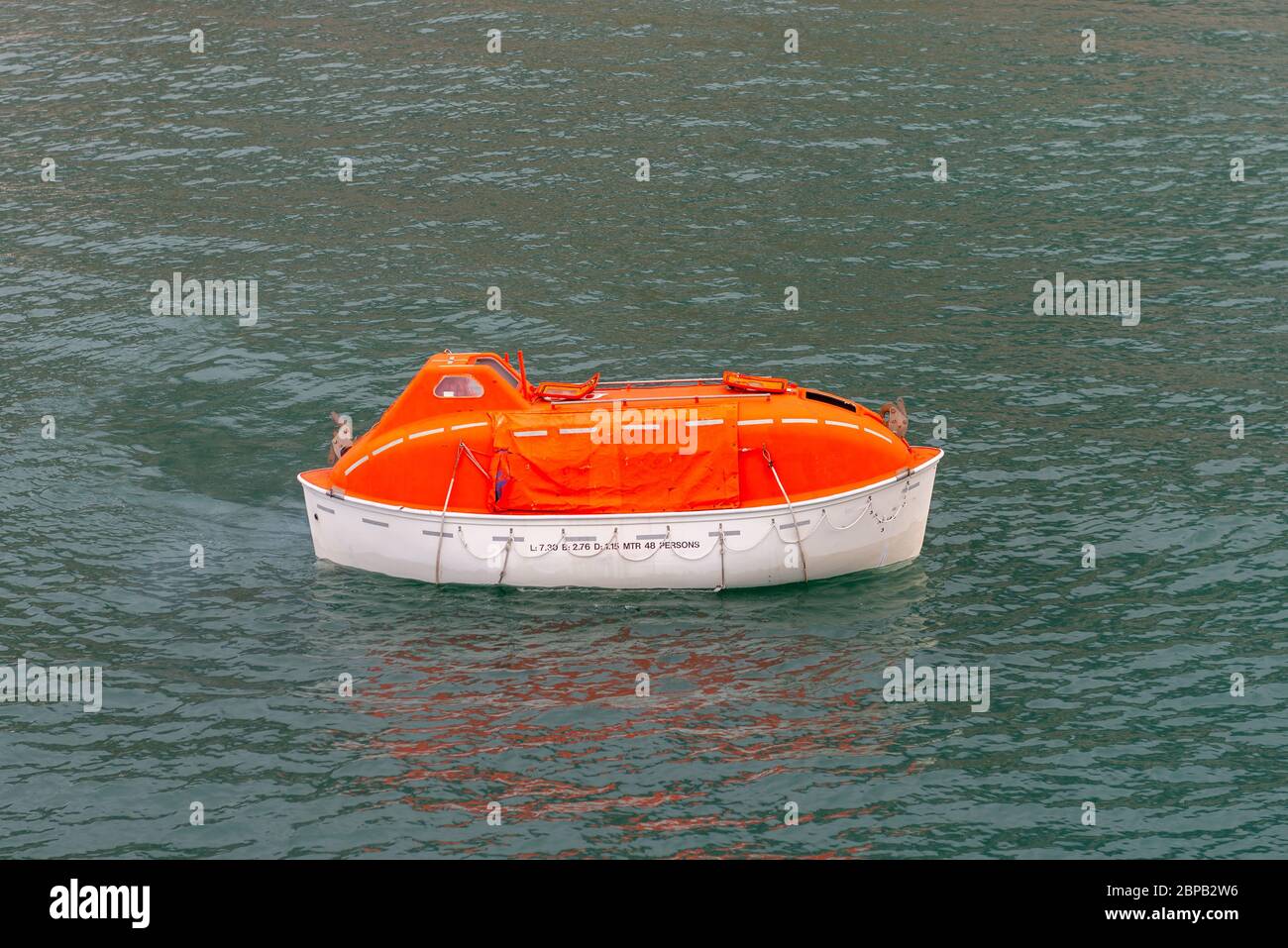 Maneuvering orange lifeboat in water in Arctic waters, Svalbard ...