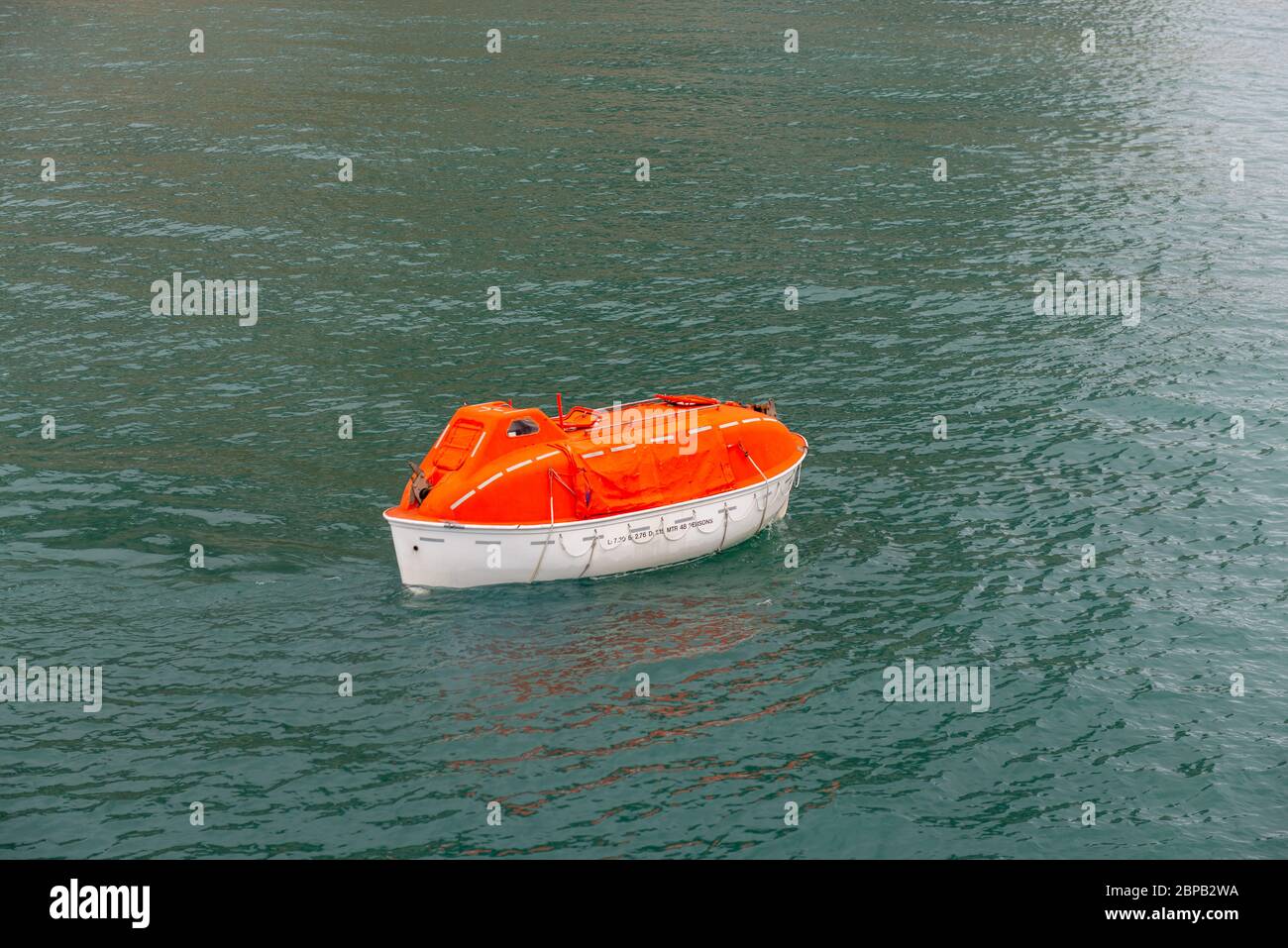 Maneuvering orange lifeboat in water in Arctic waters, Svalbard ...