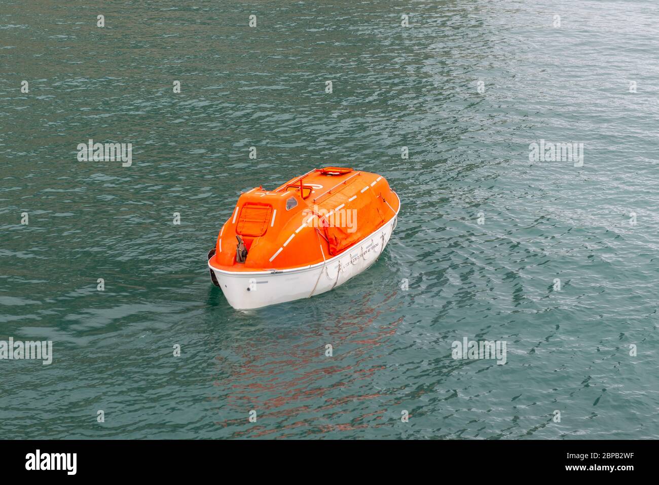 Maneuvering orange lifeboat in water in Arctic waters, Svalbard ...