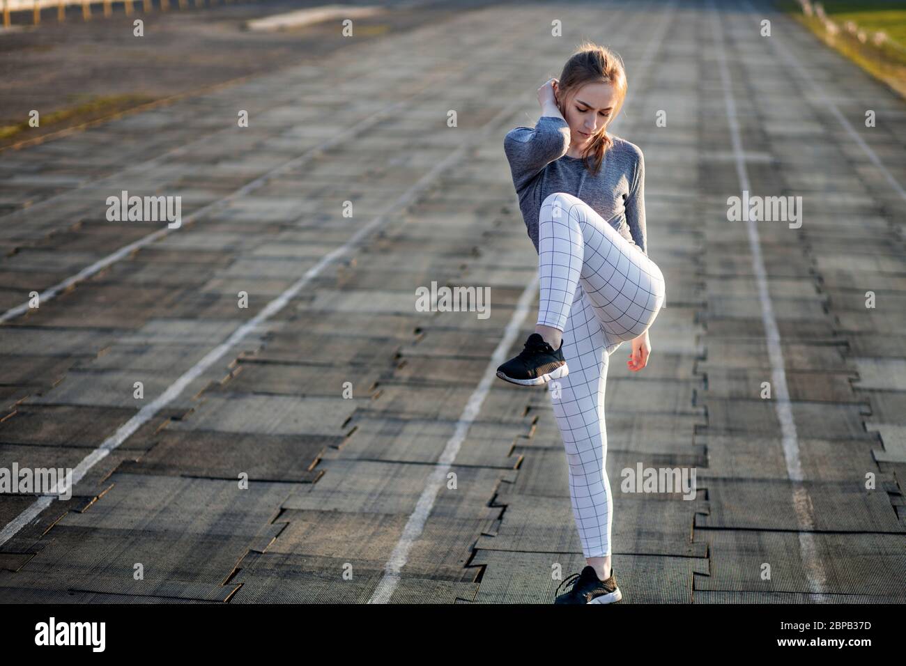 Female runner stretching legs on running track Stock Photo - Alamy