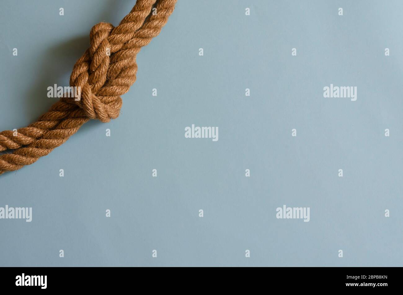 Hemp rope with a nautical knot on a light blue background. Knotted ...