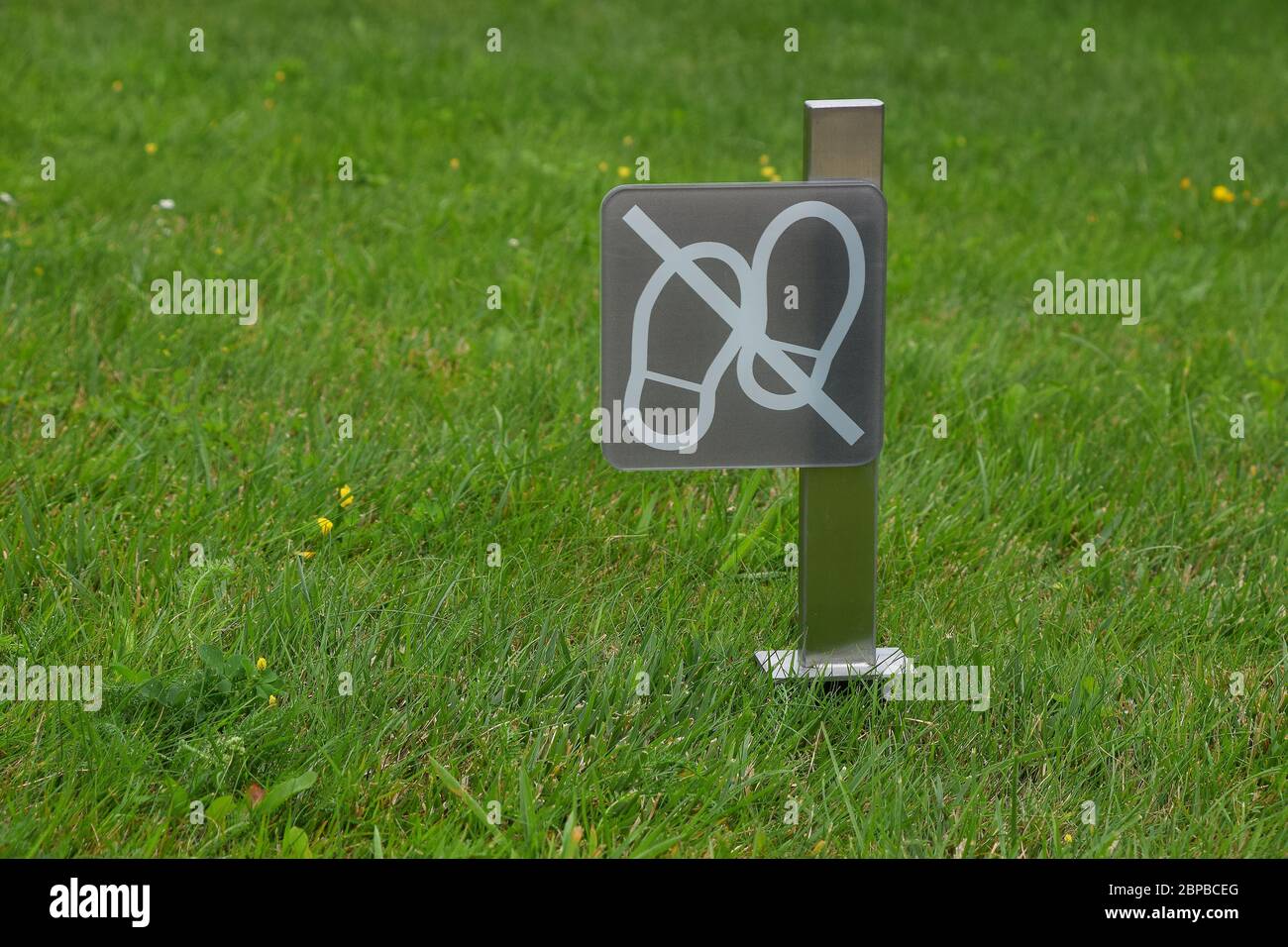 Close up keep off the grass warning sign over green lawn background ...