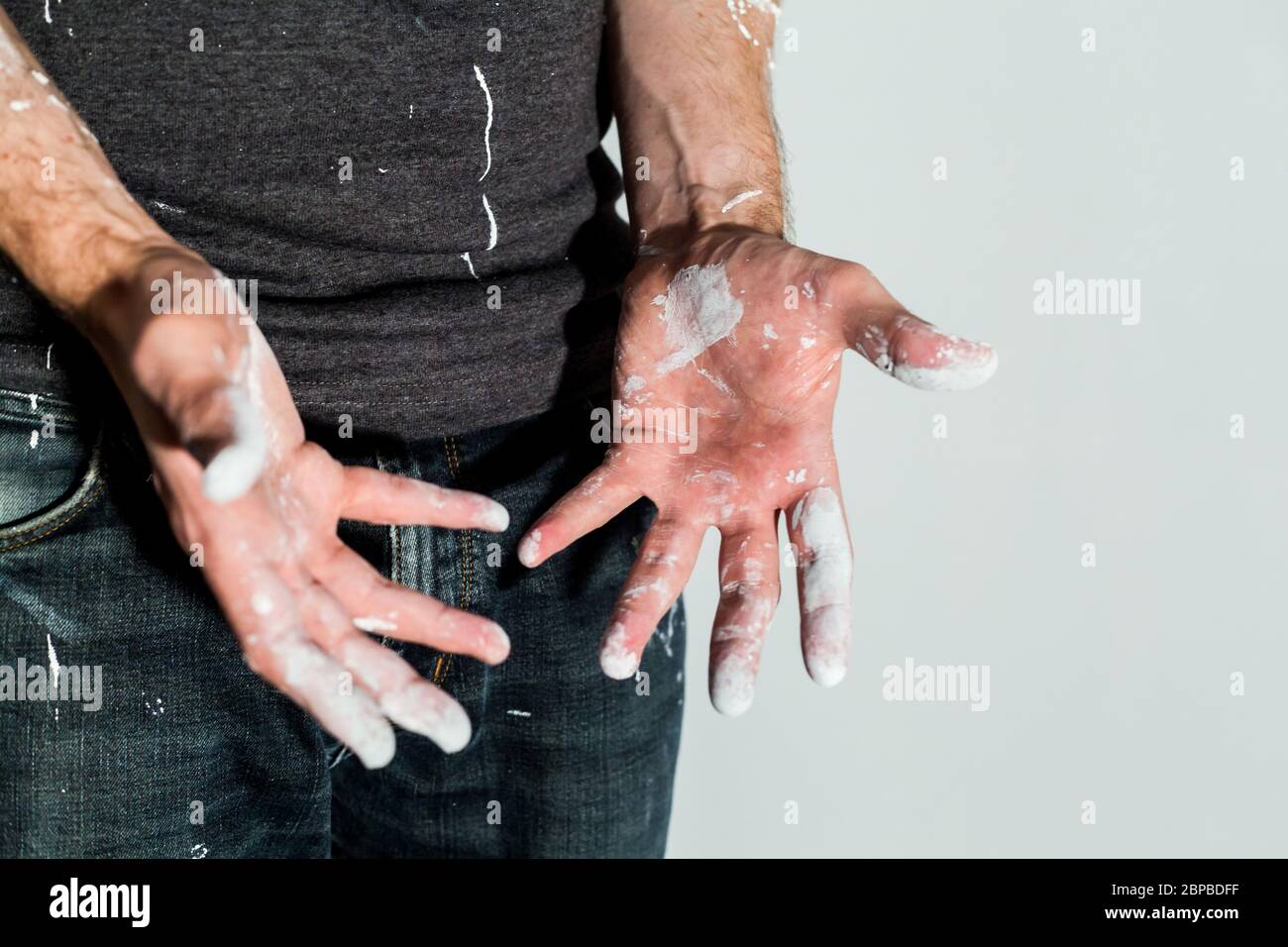 Craftsman with white paint particle at hands and clothes after painting ...