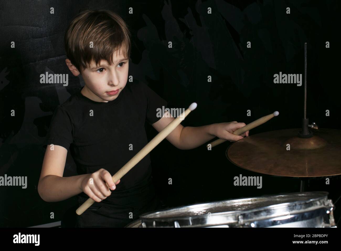 The child behind the drum. A boy with drumsticks behind a drum kit ...