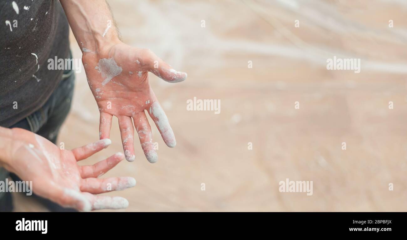 Craftsman with white paint particle at hands and clothes after painting ...