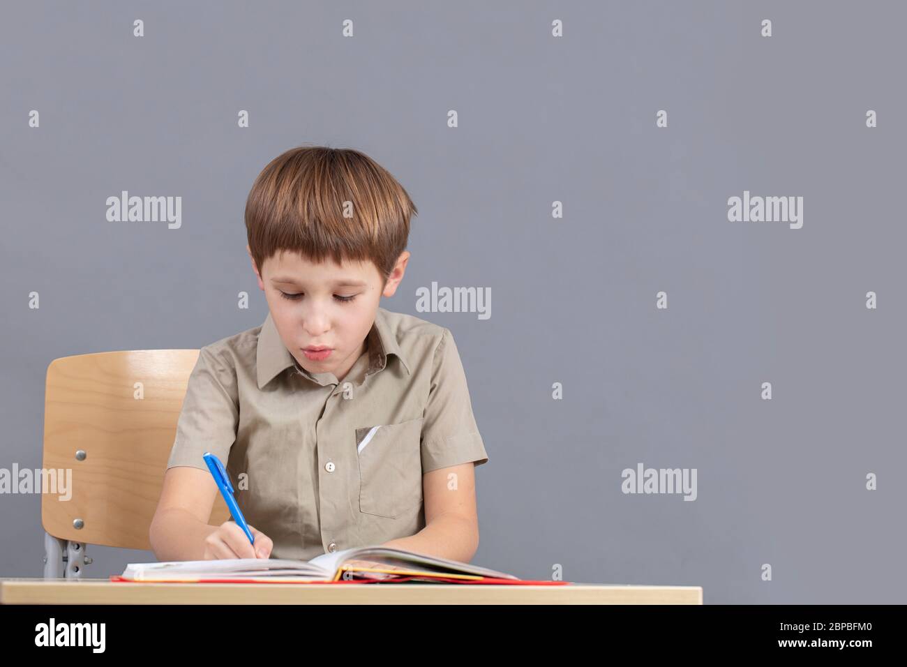 The child at the table is doing homework. Primary school student with a ...