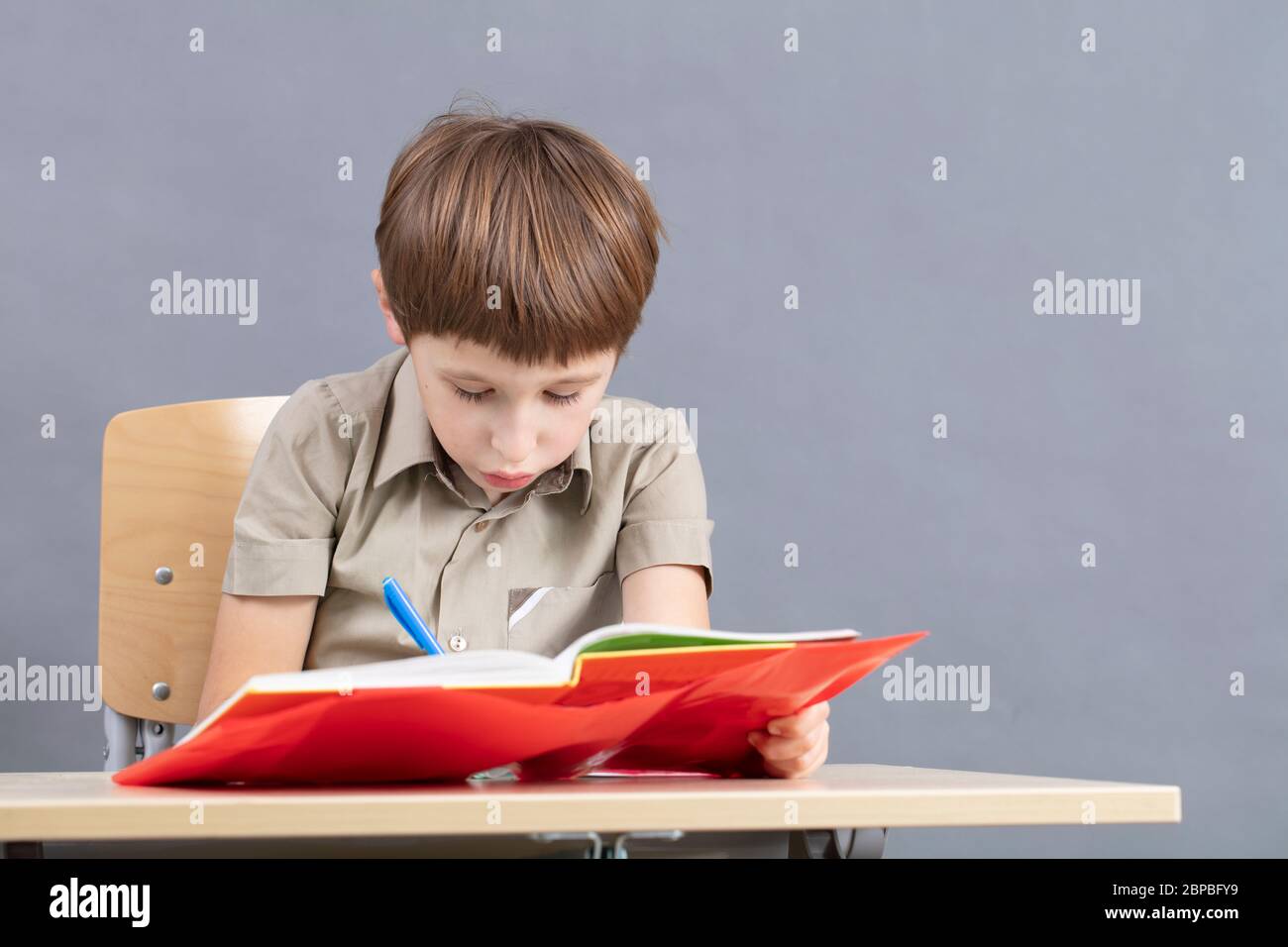 The child at the table is doing homework. Primary school student with a ...
