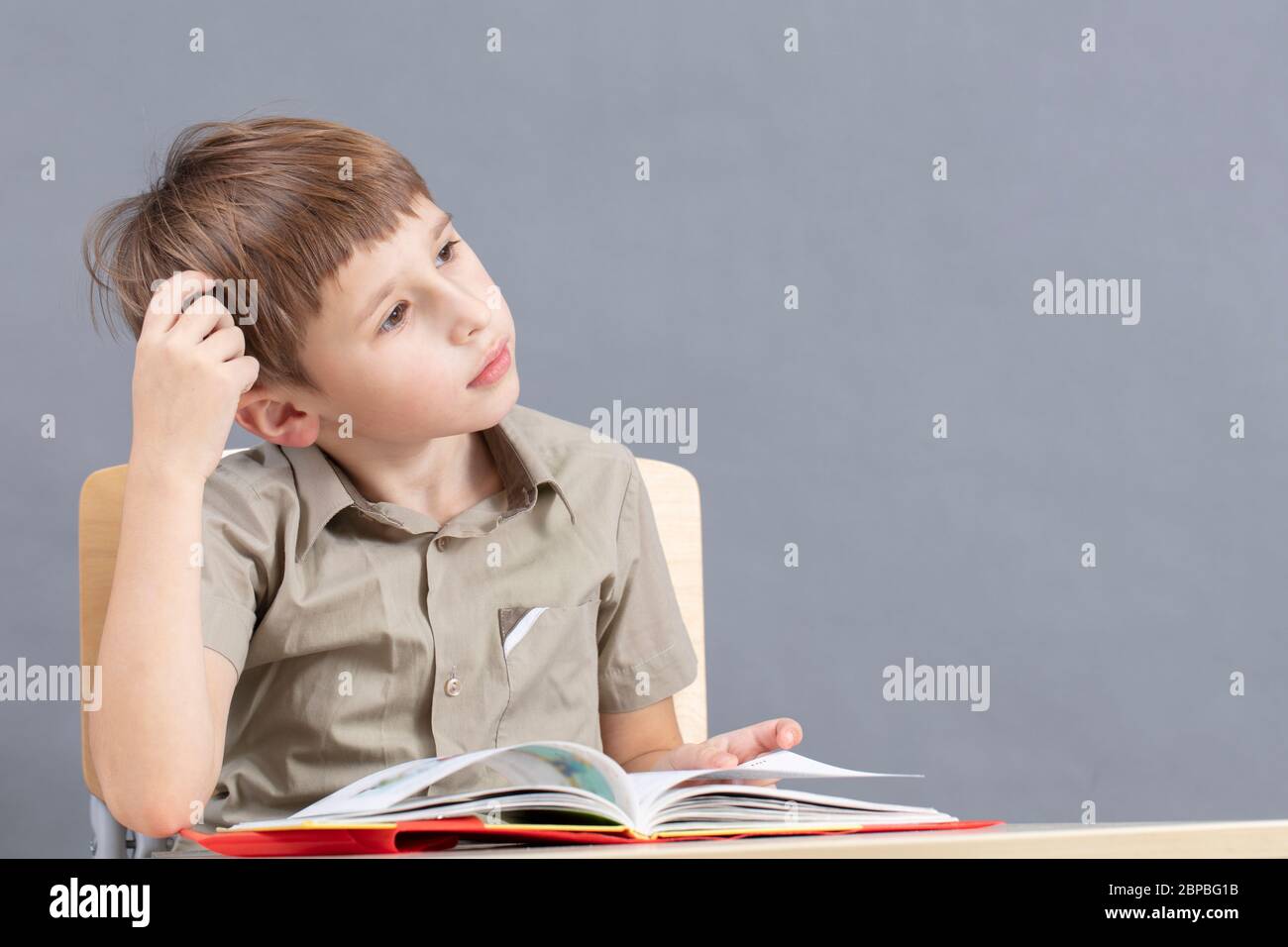 The child at the table is doing homework. Primary school student at a ...