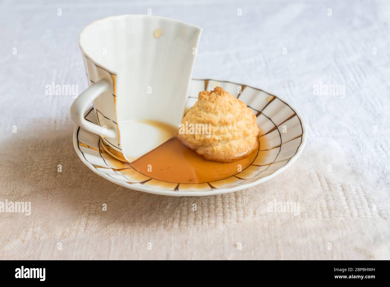 broken porcelain cup with tea and cookie on cotton tablecloth Stock ...