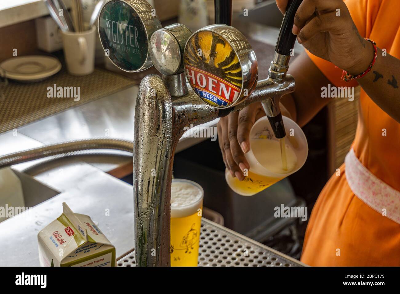 Mauritius, January 2020 - Close up chrome tap with bartender holding a ...