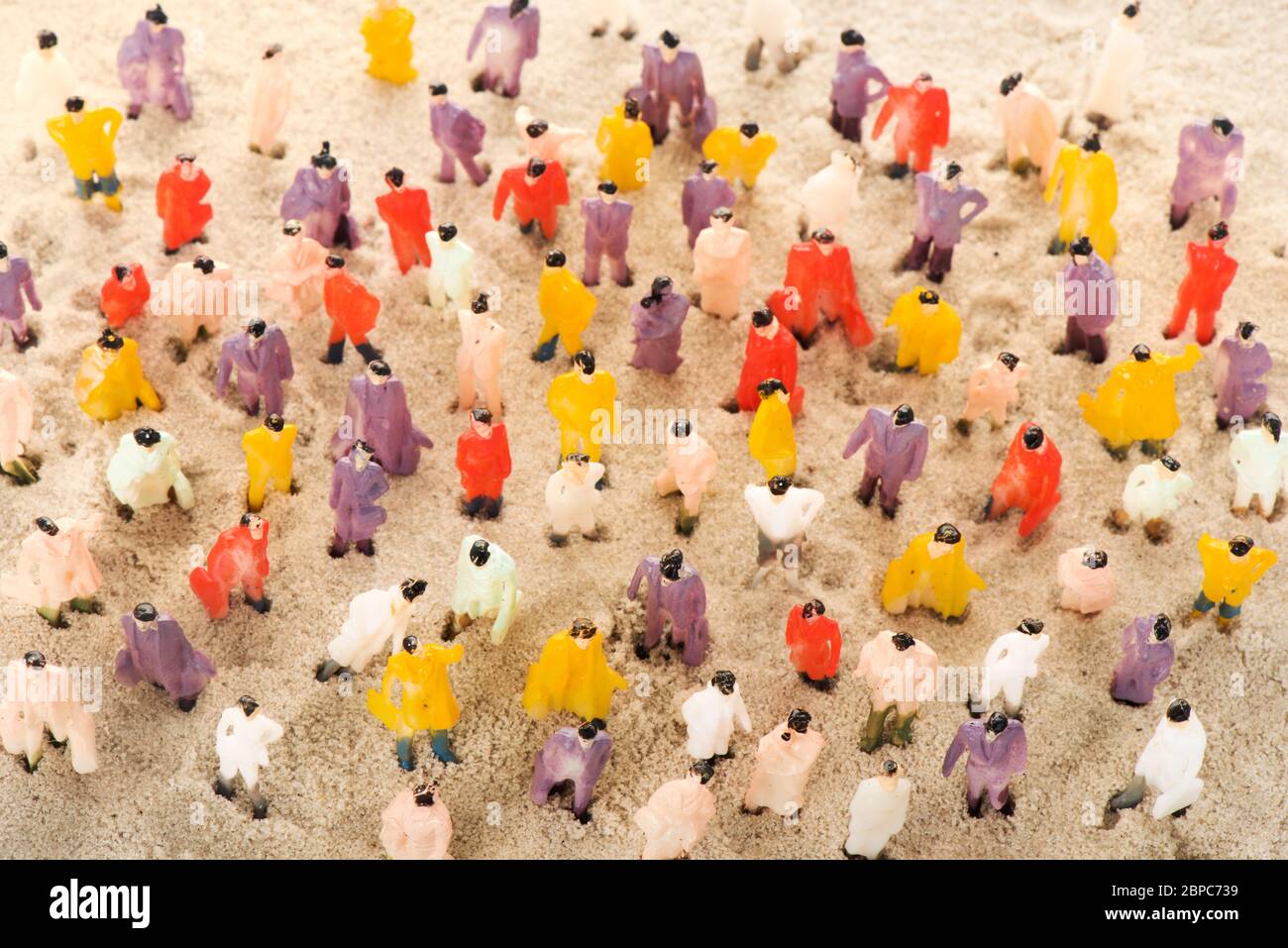 Crowd of many little figurines in sand Stock Photo - Alamy