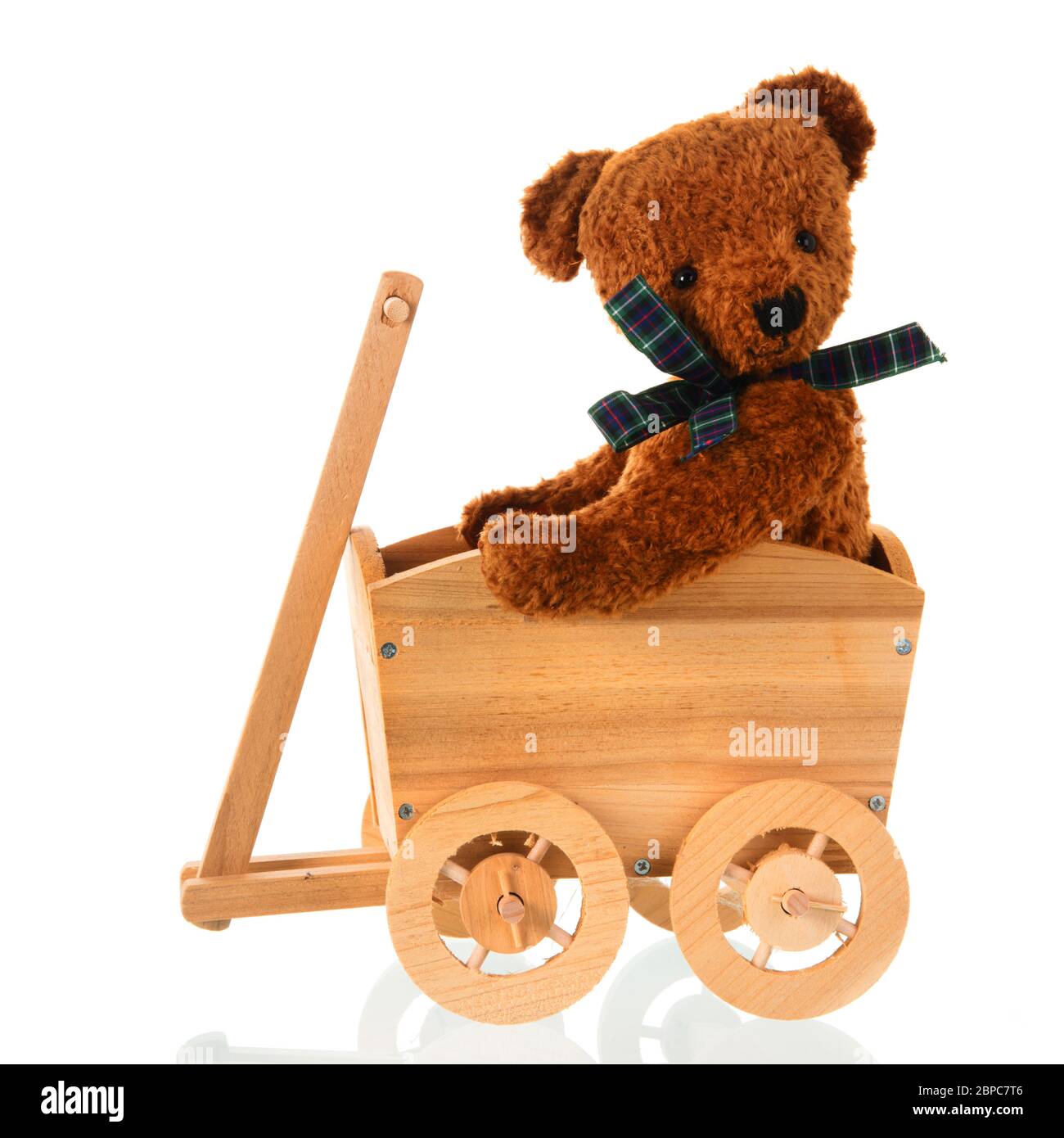 Stuffed bear toy with bow sitting in wooden cart isolated over white ...