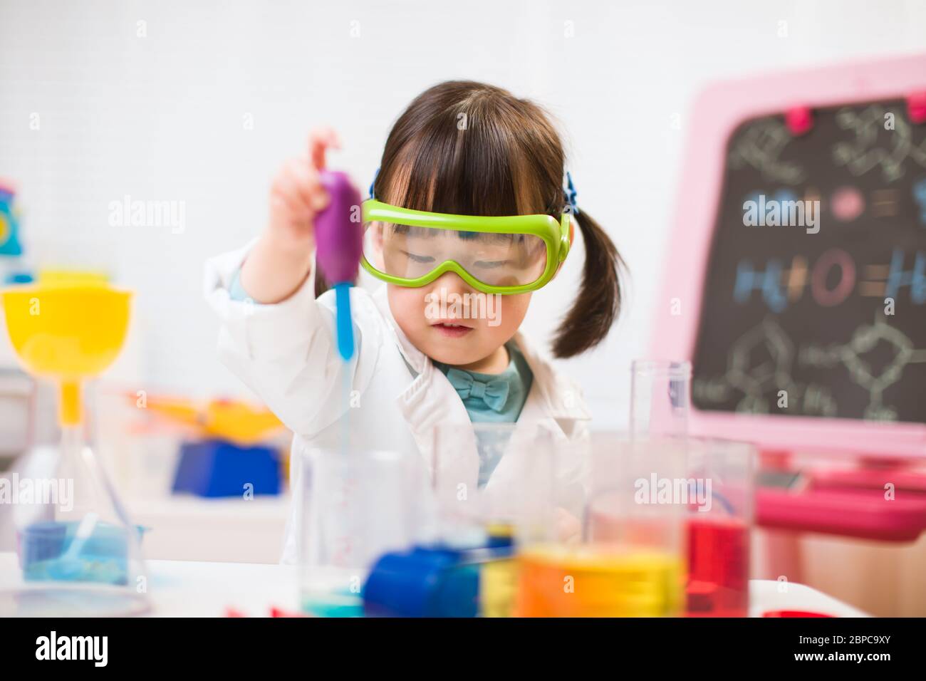 toddler girl pretend play scientist role at home against white ...