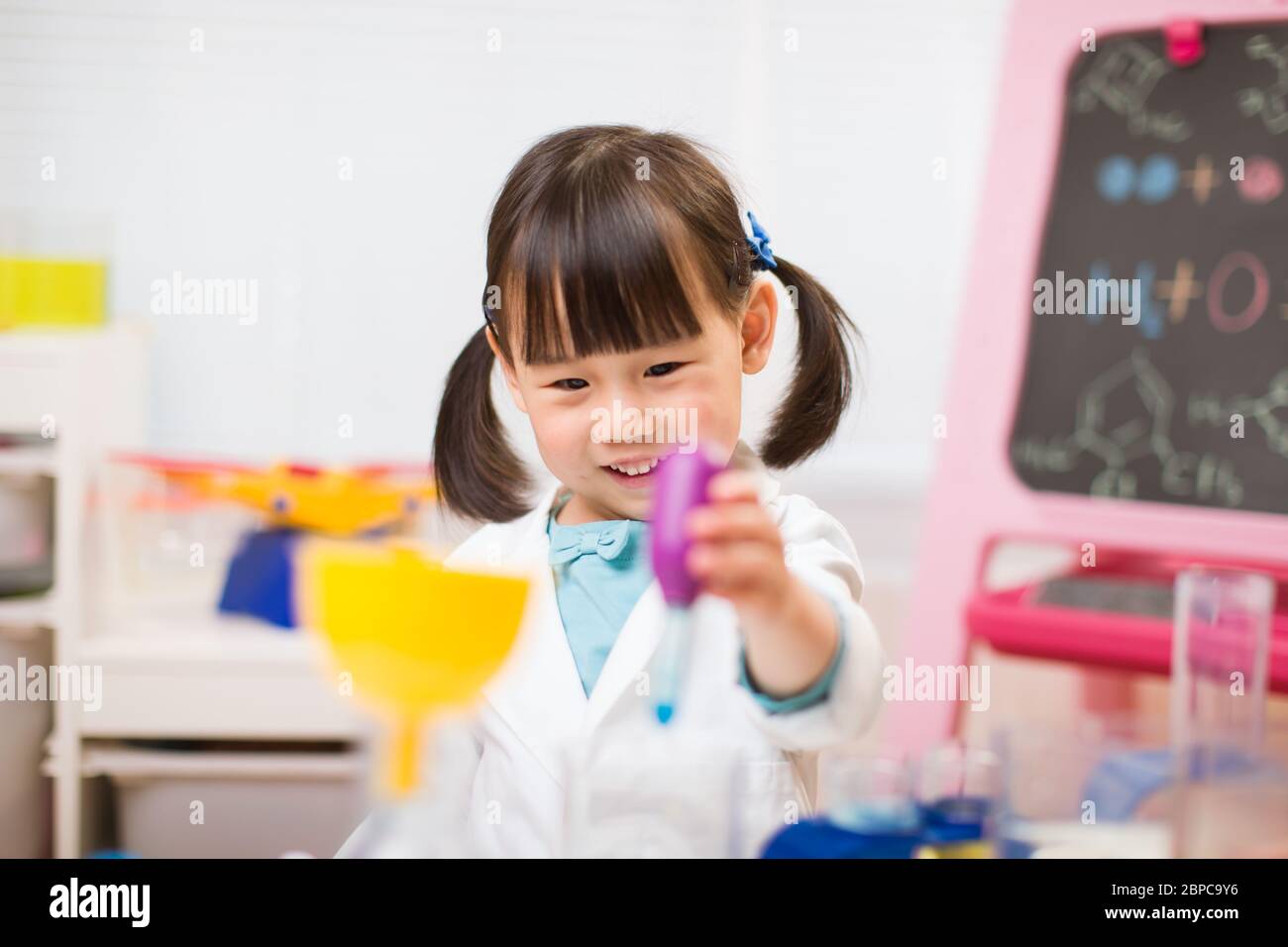 toddler girl pretend play scientist role at home against white ...