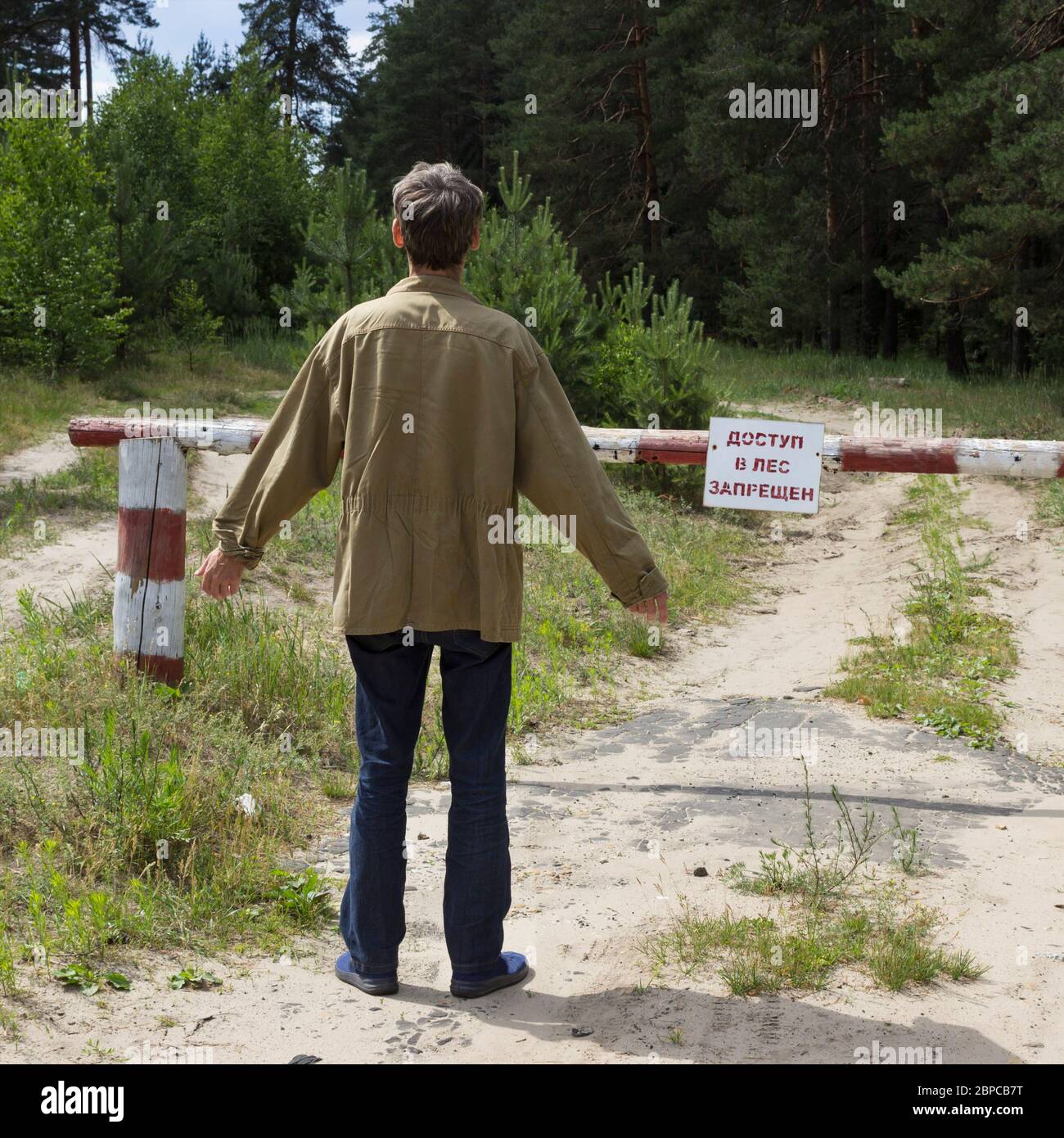 Man stands in front of a barrier in the forest in fire-dangerous period ...