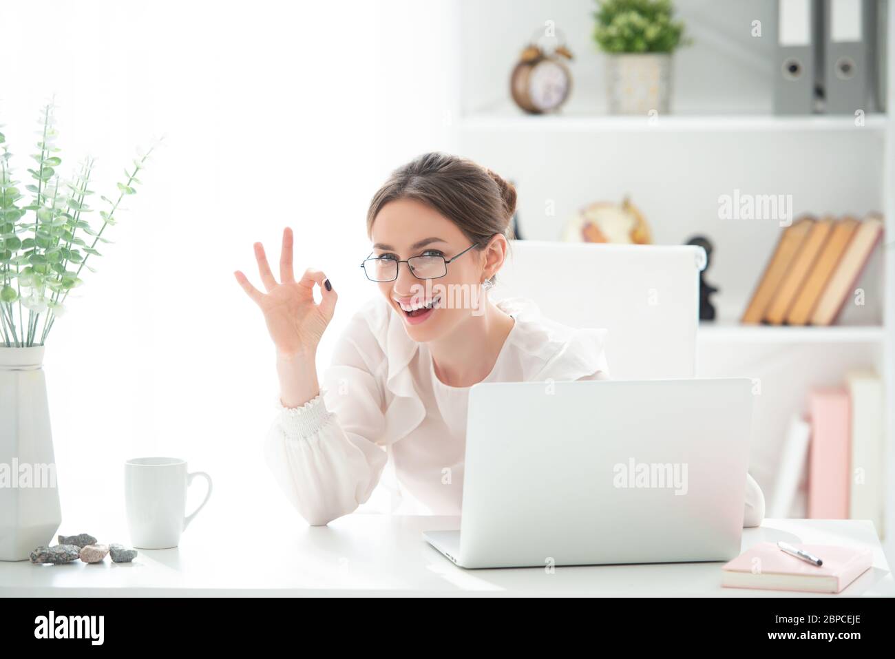 Smiling young woman in the office is very happy from a successful order ...