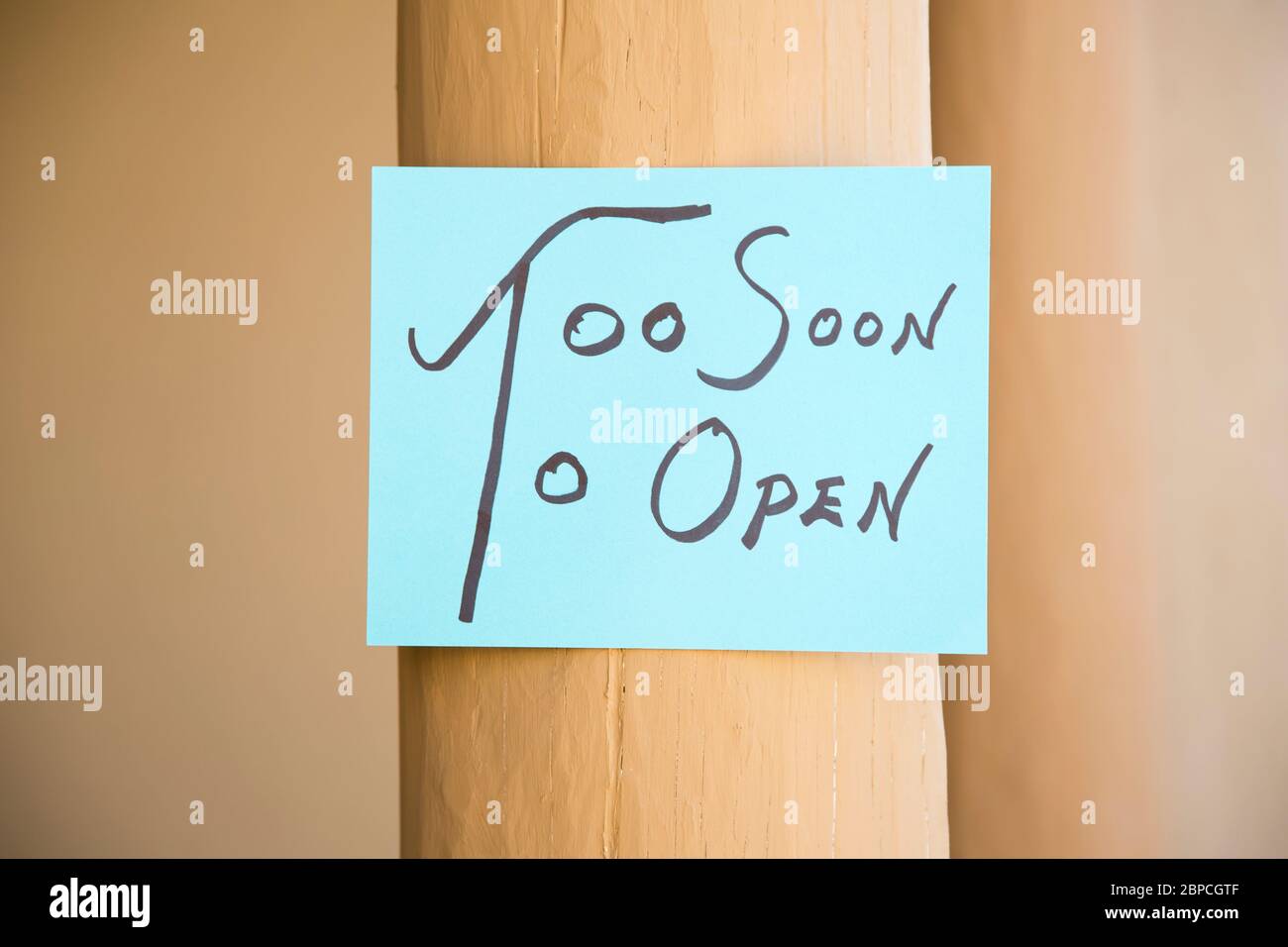 Blue paper, hand written announcement sign of Too Soon To Open attached ...