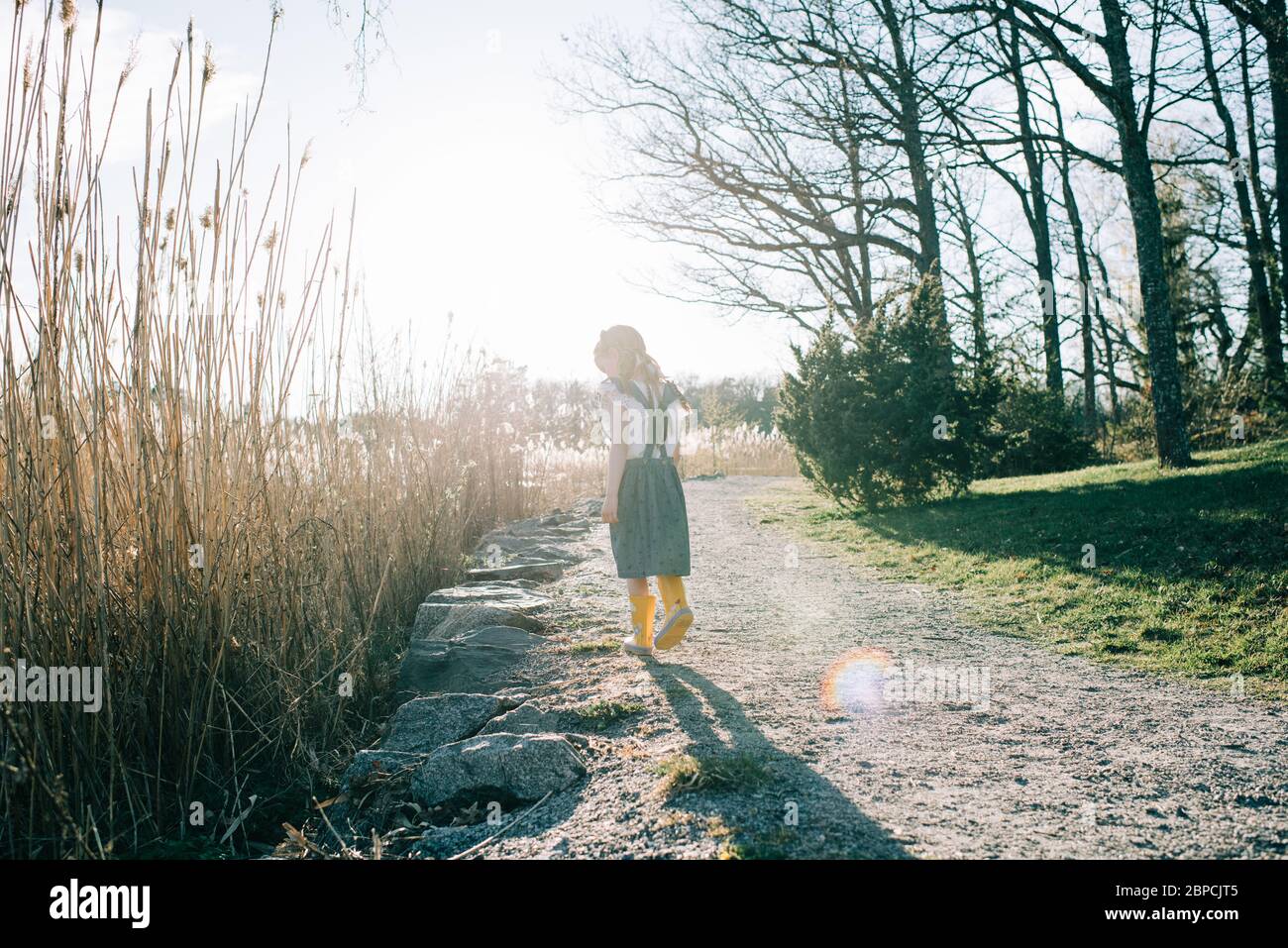 young girl walking along a coastal path in a dress at sunset Stock ...